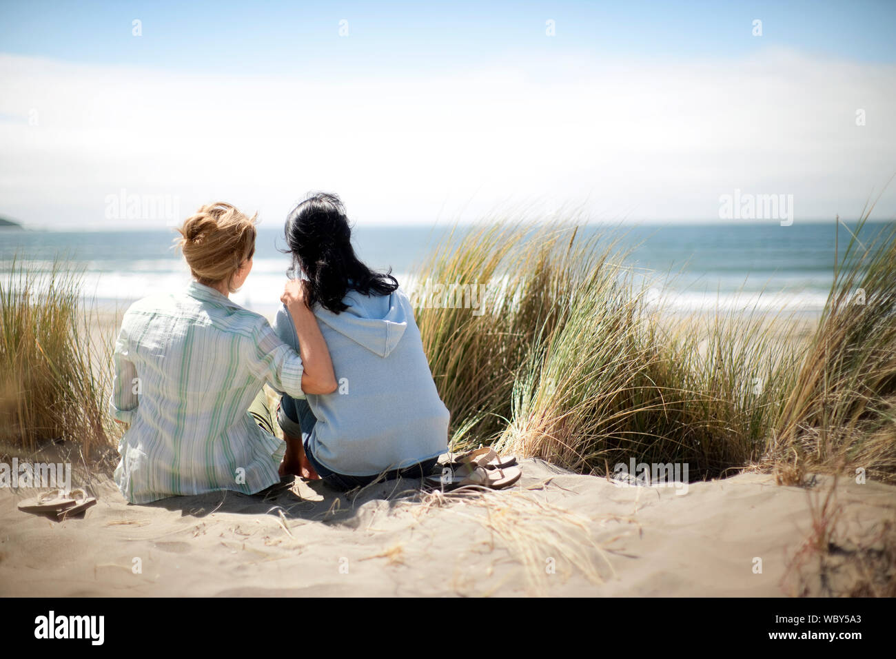 Two friends sitting watching the ocean Stock Photo - Alamy