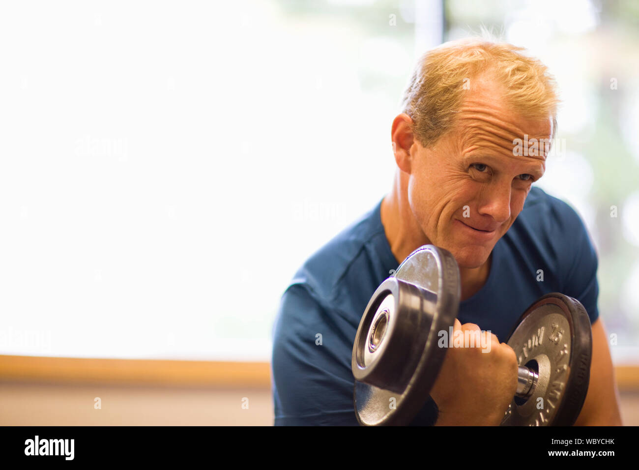 Mid-adult man lifting weights in a gym Stock Photo - Alamy