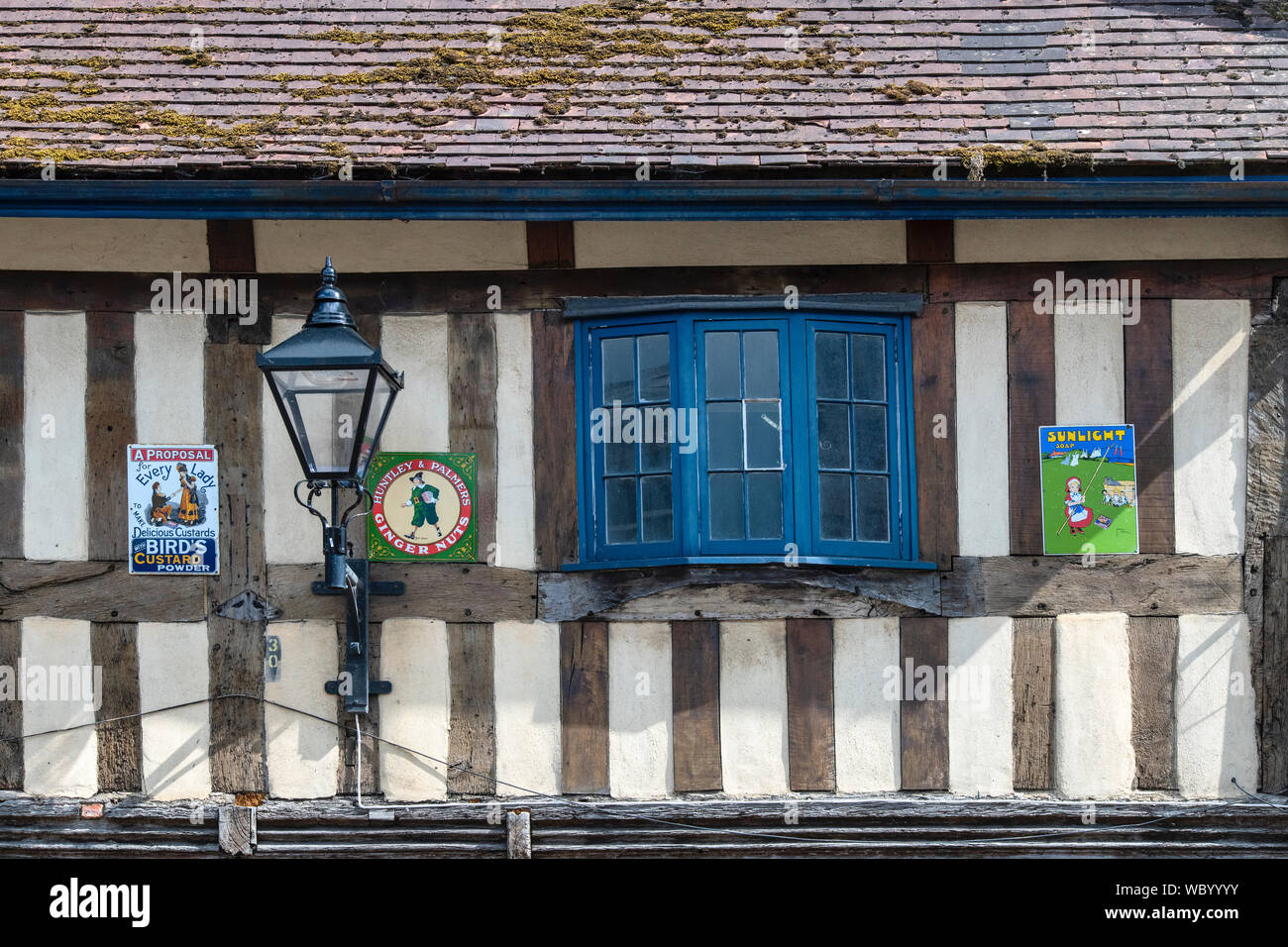 Old signs and street lamp on a timber framed building in Winchcombe ...