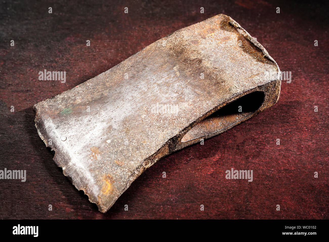 Close up photograph of battered old ax head without handle against dark ...