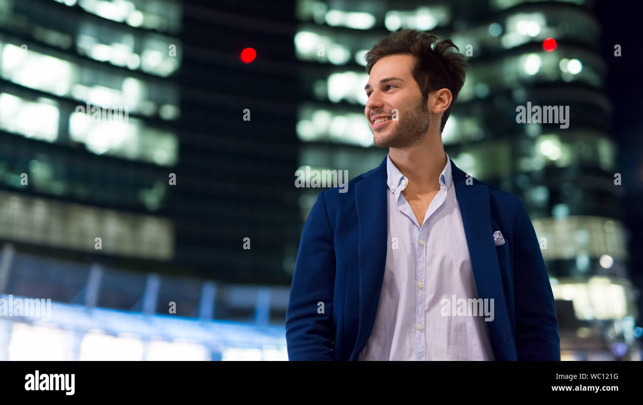 Smiling young man walking outdoors at night Stock Photo - Alamy