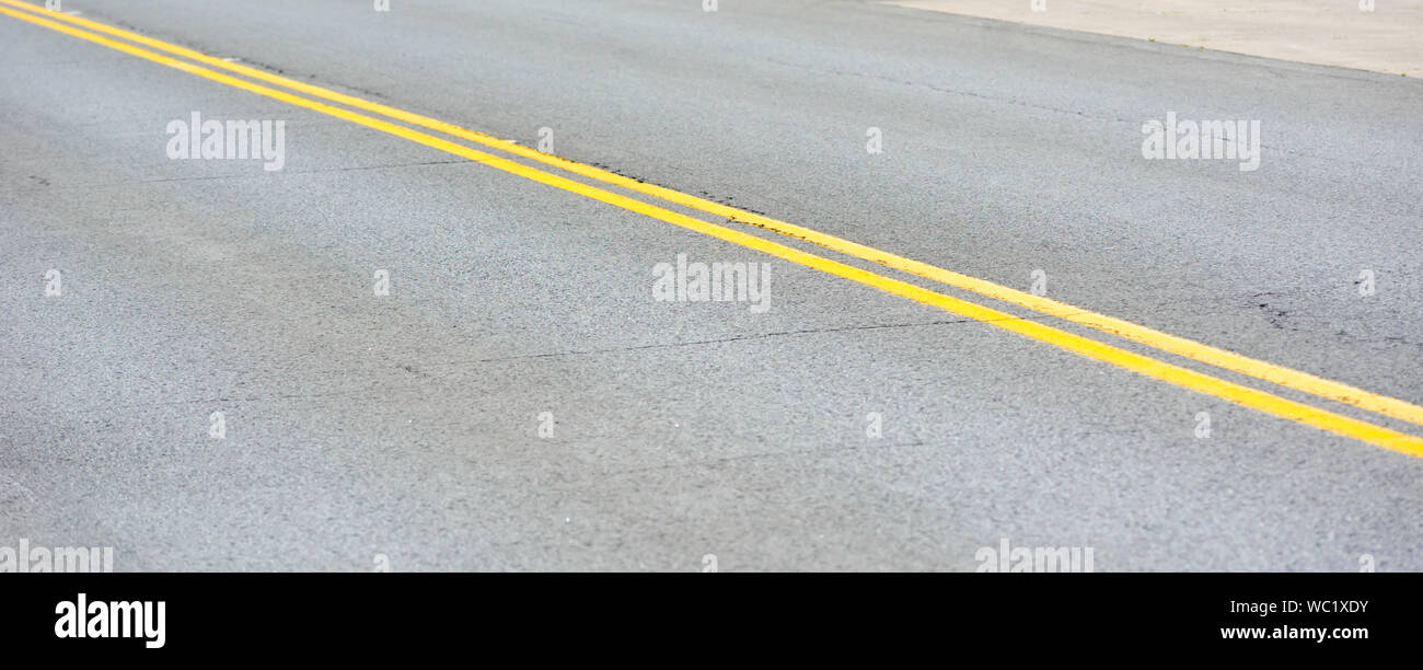 Pair of yellow lines on gray asphalt road angled diagonally Stock Photo ...