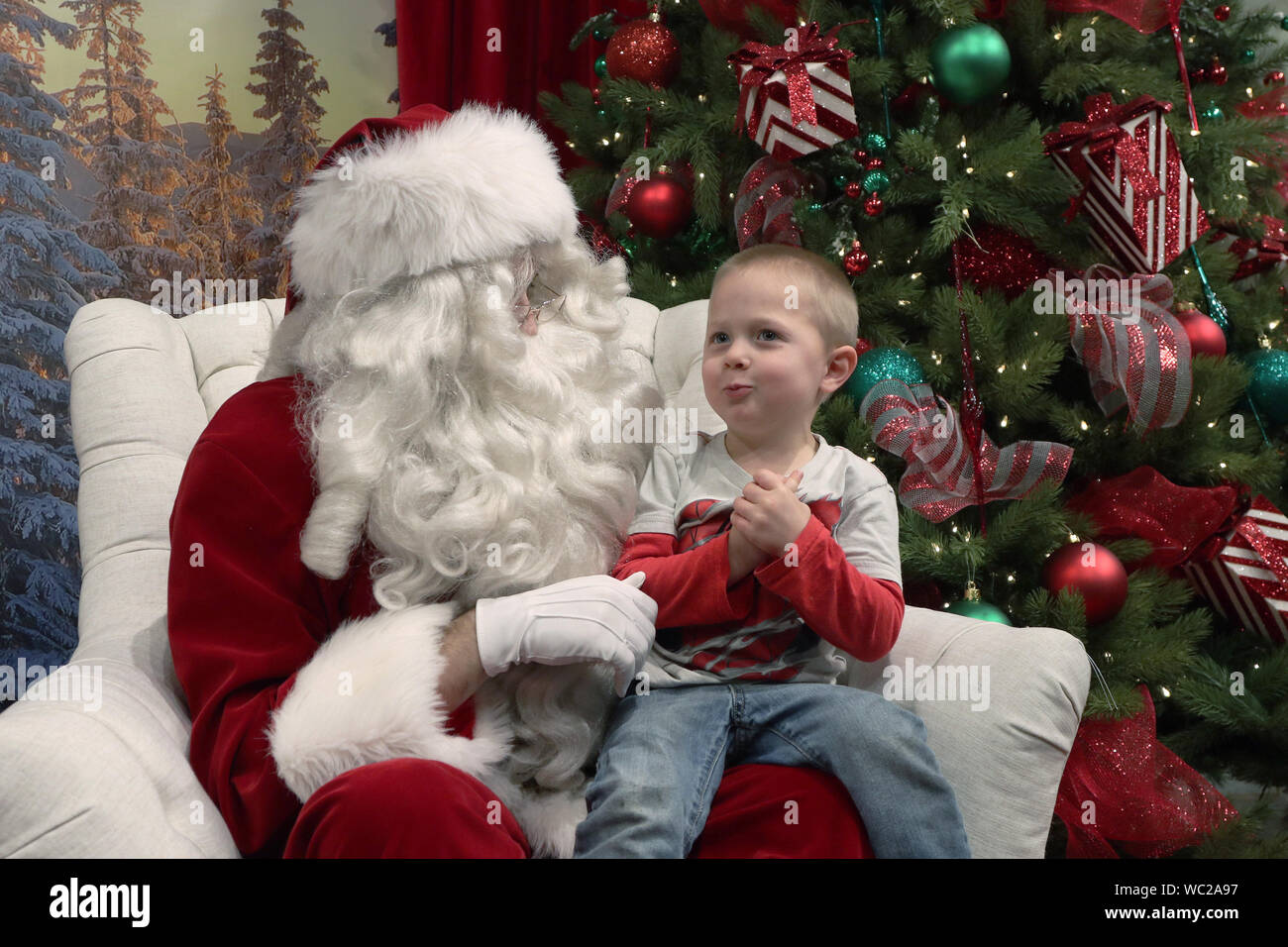 Boy sitting on Santa Clause's lap telling Santa what he wants Stock ...