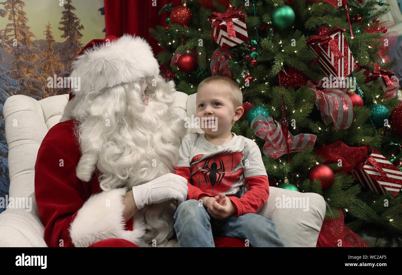 Boy sitting on Santa Clause's lap telling Santa what he wants Stock ...