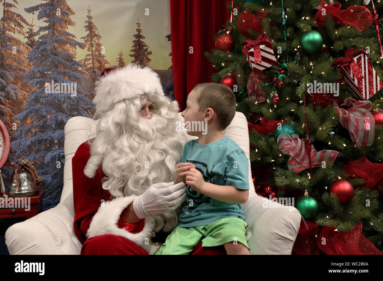 Boy sitting on Santa Clause's lap telling Santa what he wants Stock ...