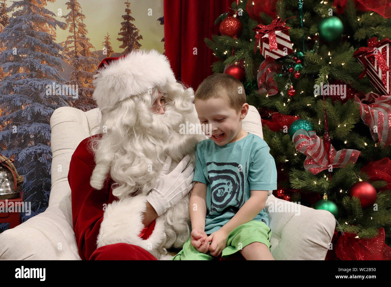 Boy sitting on Santa Clause's lap telling Santa what he wants Stock ...