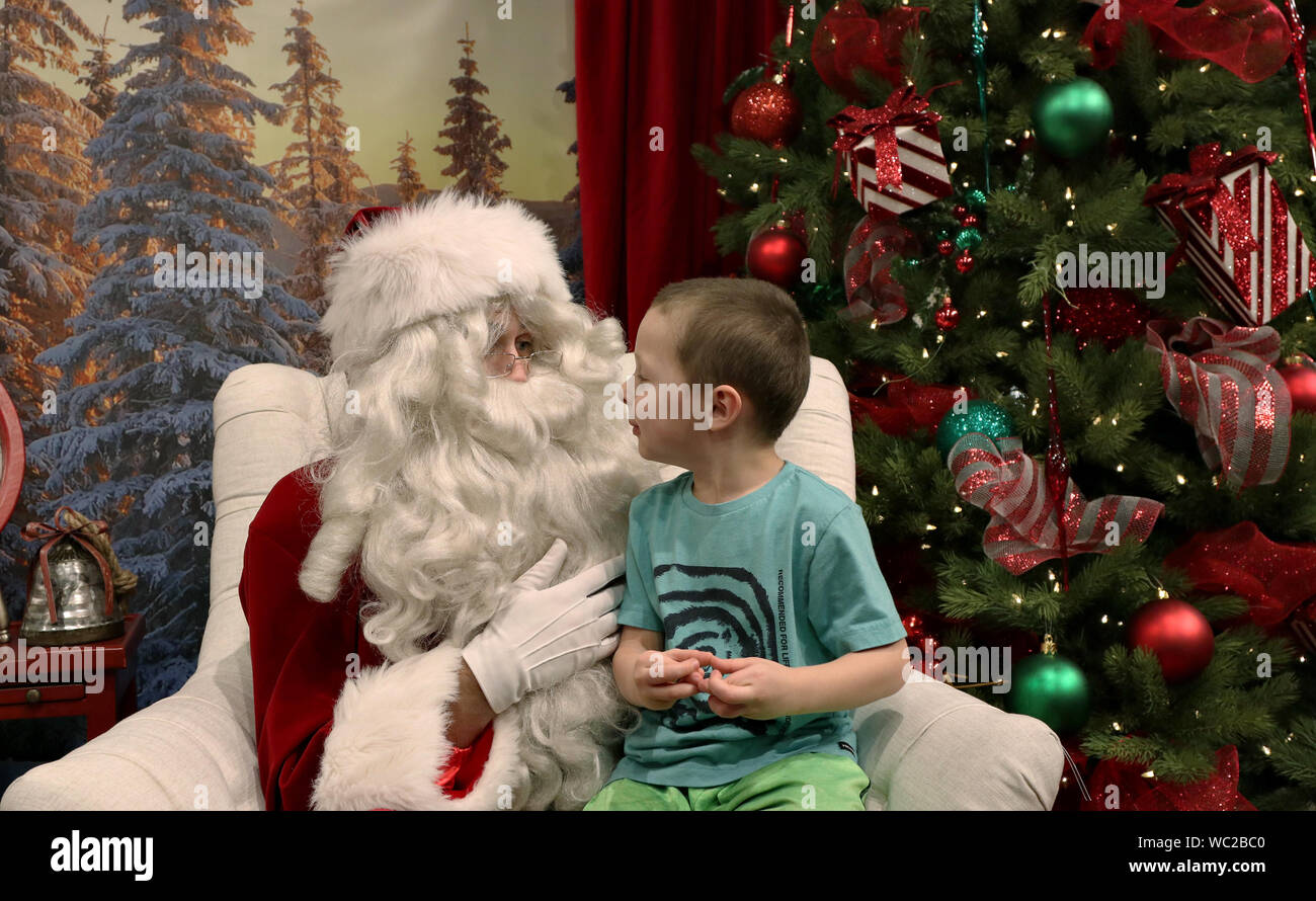 Boy sitting on Santa Clause's lap telling Santa what he wants Stock ...