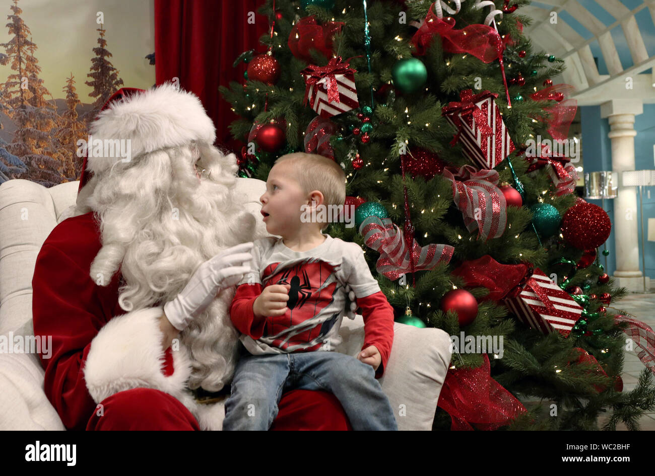 Boy sitting on Santa Clause's lap telling Santa what he wants Stock ...