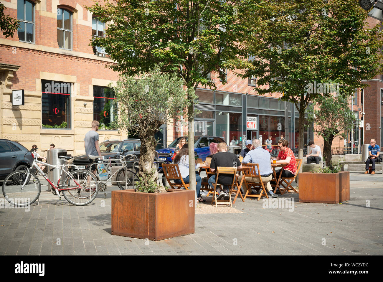 People enjoy the sunshine in a small square between Hood Street ...