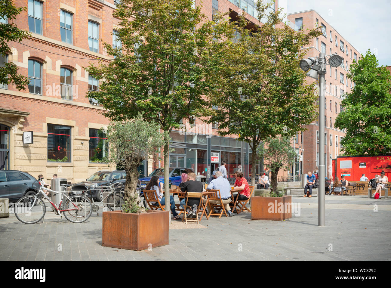 People enjoy the sunshine in a small square between Hood Street ...