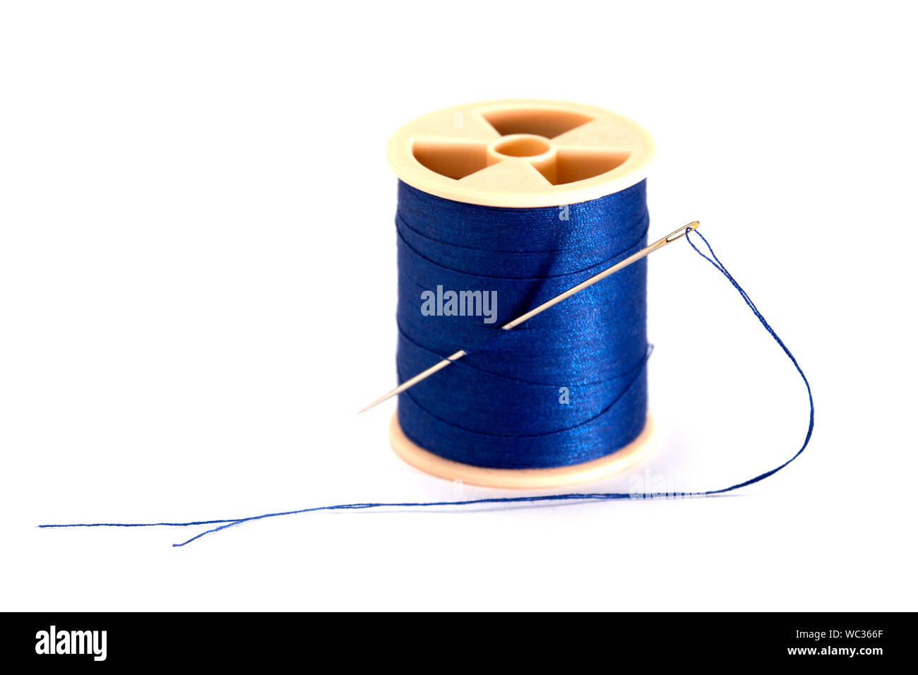 Single spool of blue thread and sewing needle on white background Stock ...