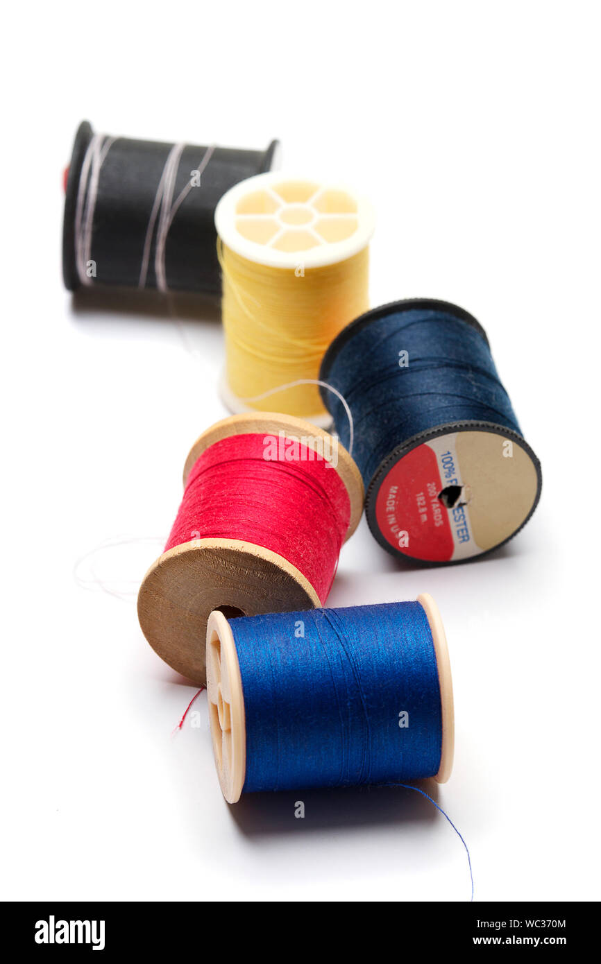 Group of spools of sewing thread in vaious stages of use and color ...
