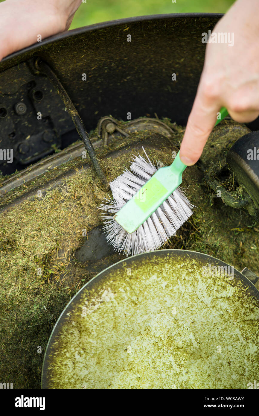Close up view of man hand brushing off layer of wet grass stuck under ...