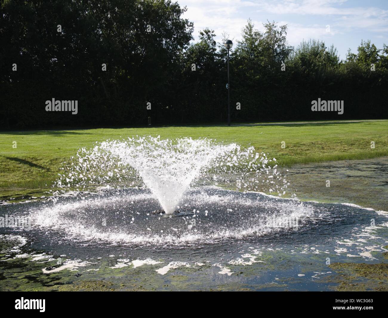 Fountain in a small lake in a park with grass in Cumbria England Stock ...