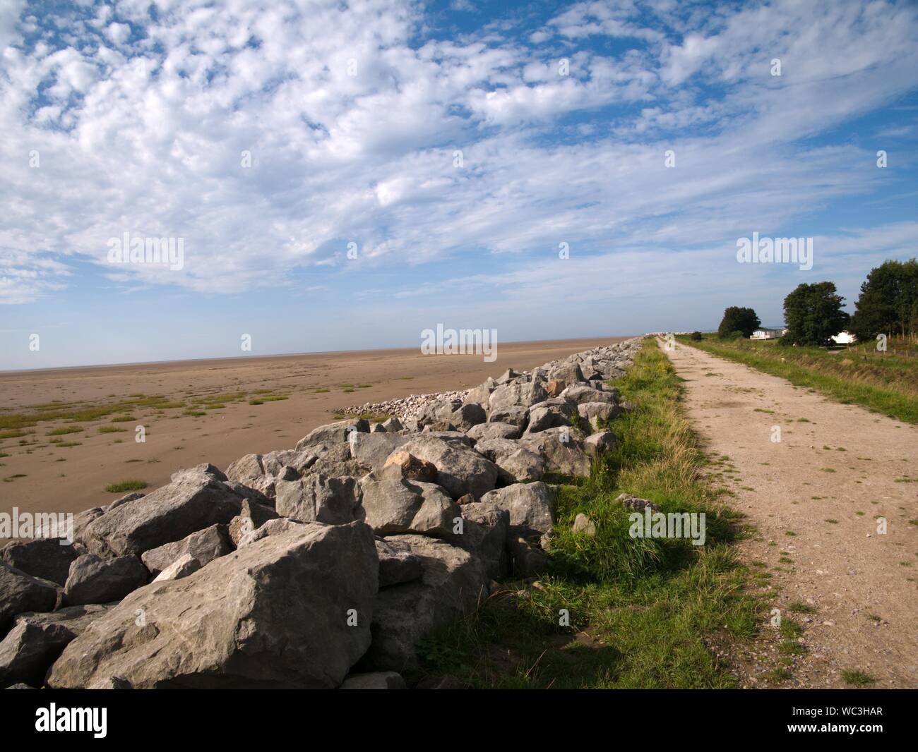 Sea defences wall along Morecambe Bay with the tide out on a sunny day ...