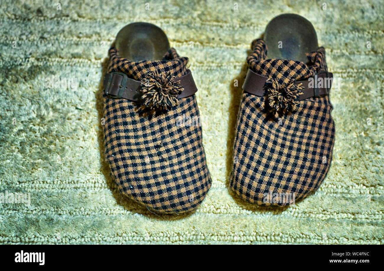 Old plaid worn slippers on an old carpet Stock Photo - Alamy