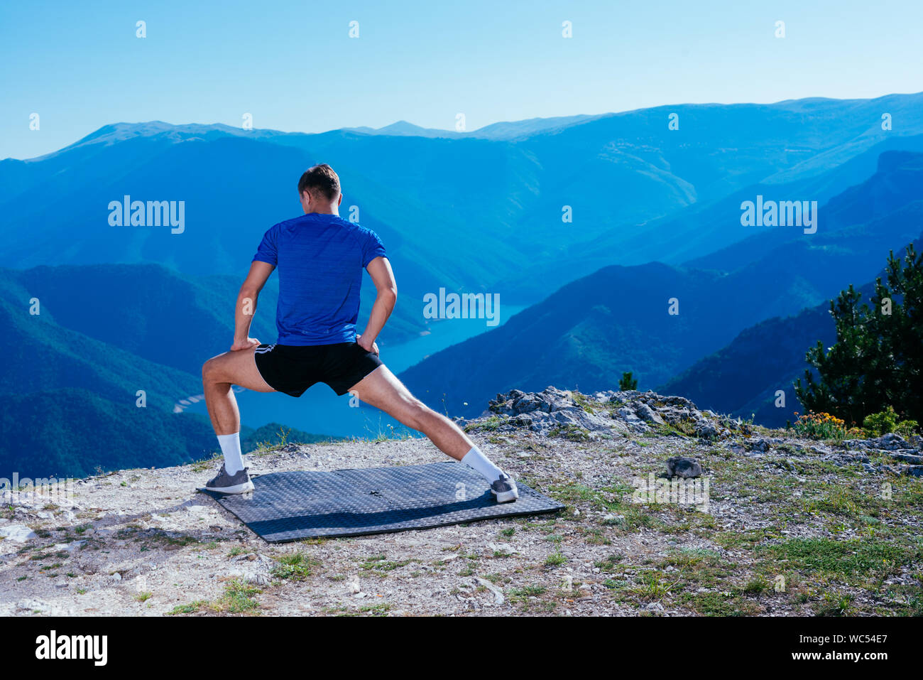 Blonde athlete wearing blue dry-fit shirt stretching and preparing for ...