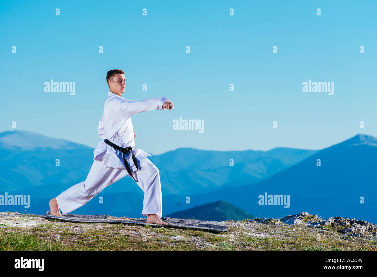 Karate man in a kimono performs a front hand kick (Choku-zuki) while ...