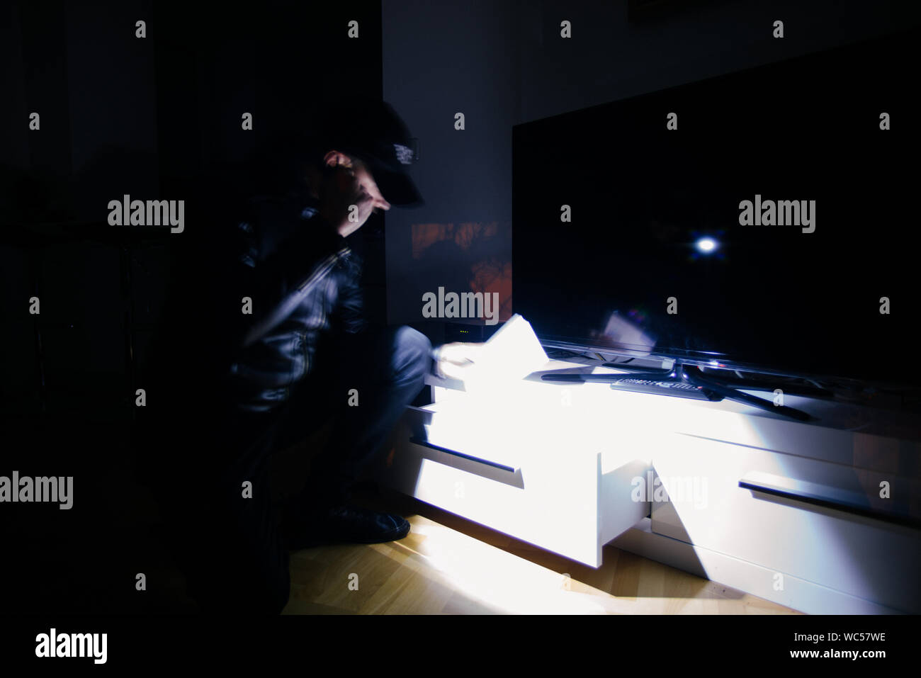 Crime scene with robber with torch in living room while stealing ...