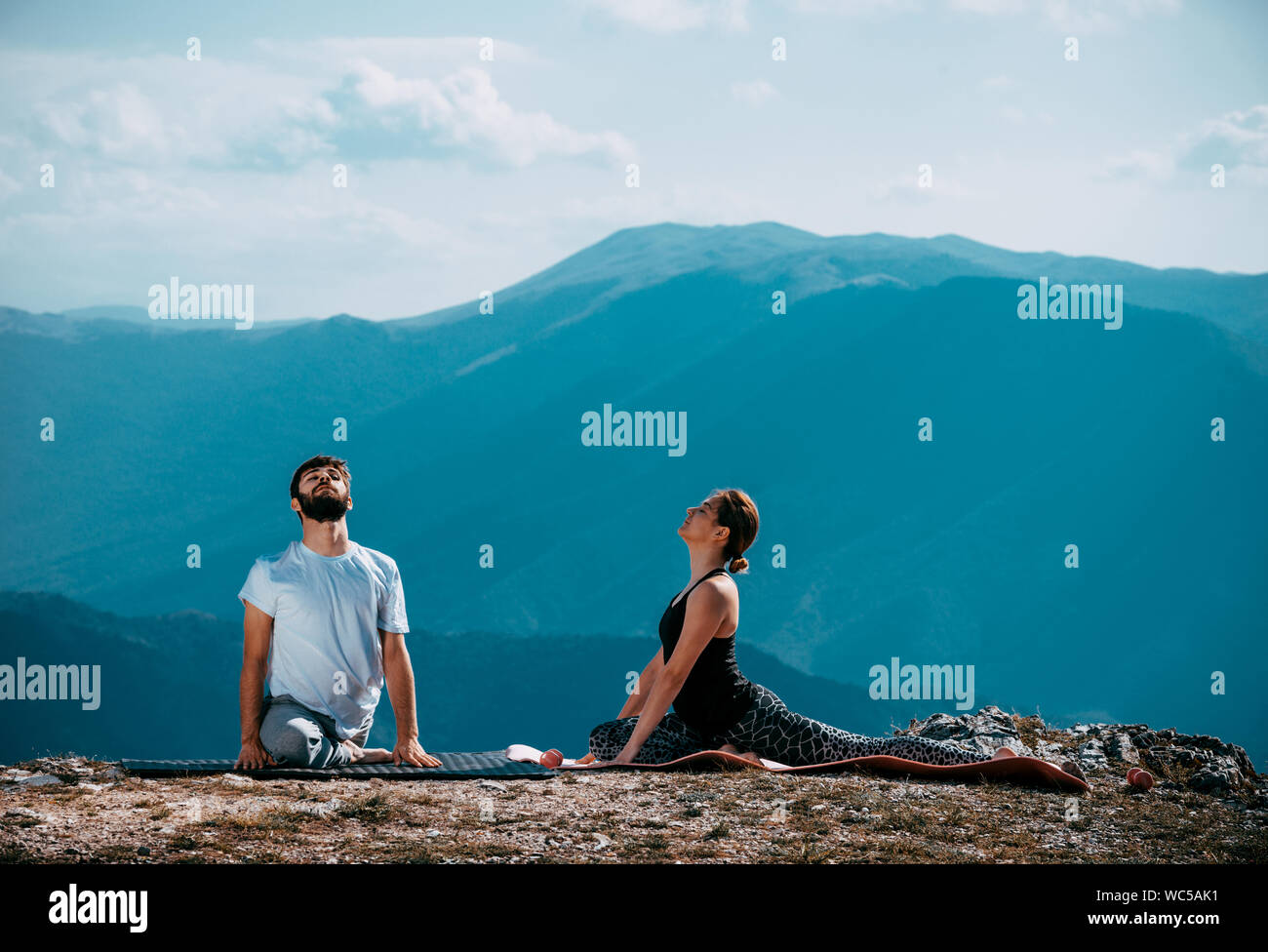 Beautiful young couple meditating in yoga pose at a big river against ...