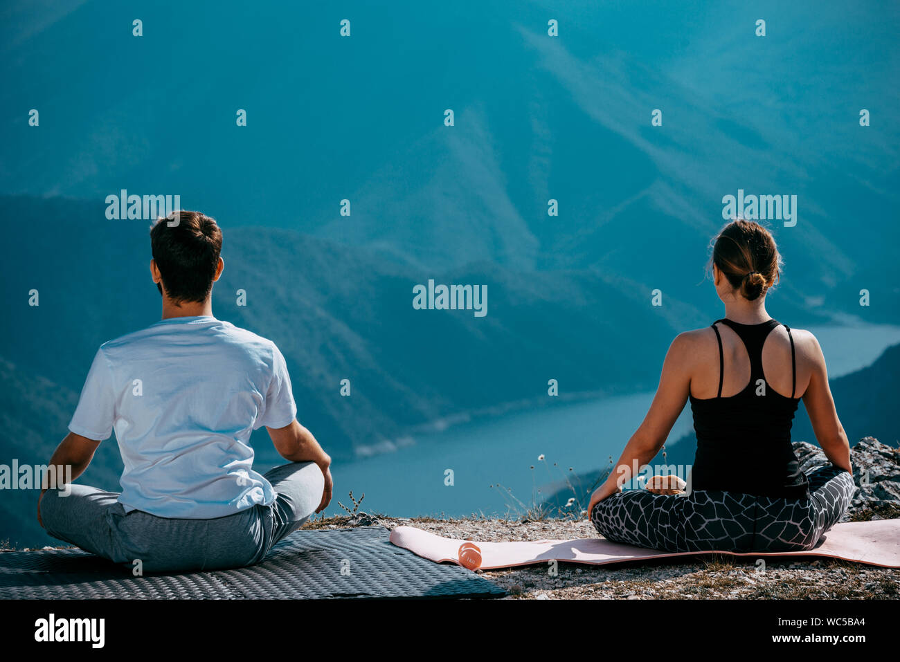 Beautiful young couple meditating in yoga pose at a big river against ...