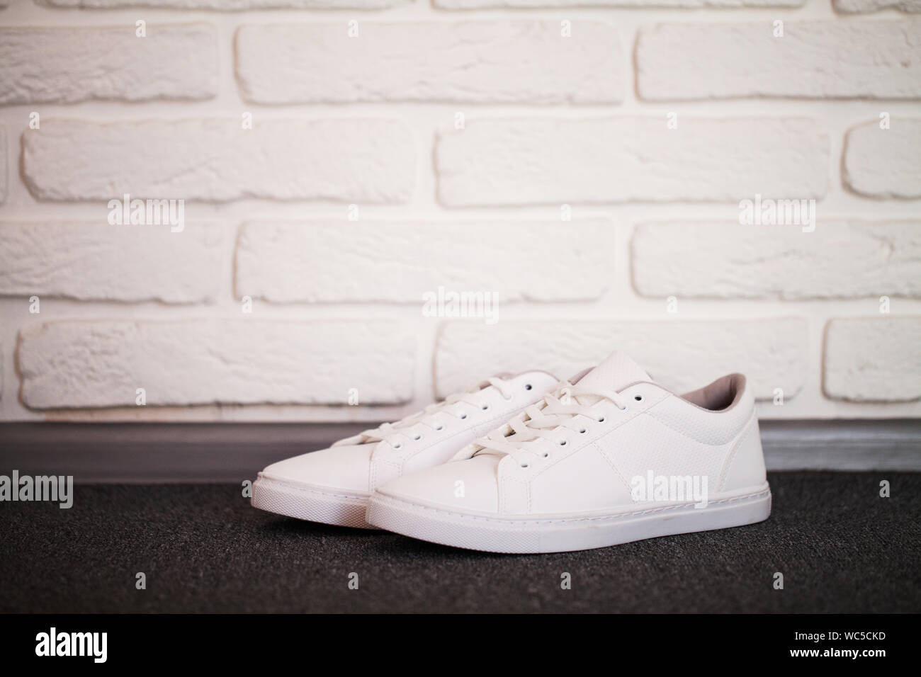 Pair of new stylish white sneakers on floor at home Stock Photo - Alamy