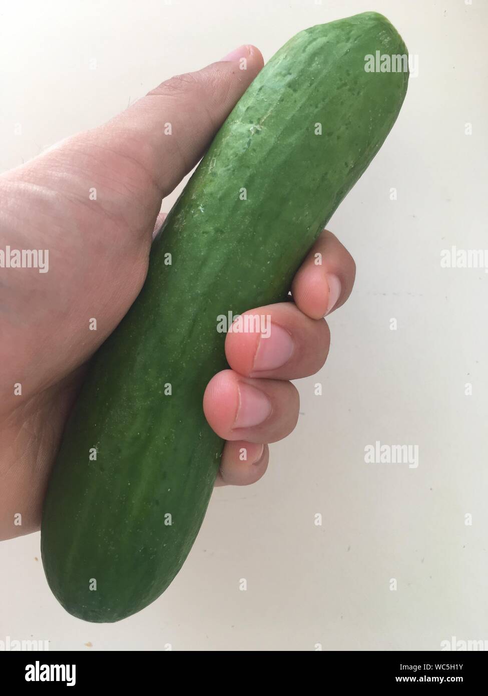 Close-up Of Hand Holding Cucumber Against White Background Stock Photo ...