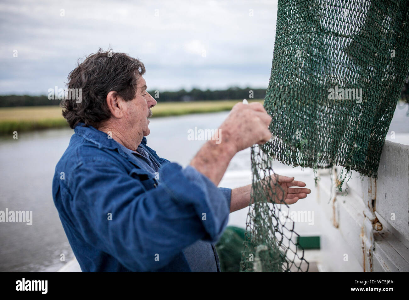 Commercial fisherman mending nets on the deck of a fishing boat Stock ...