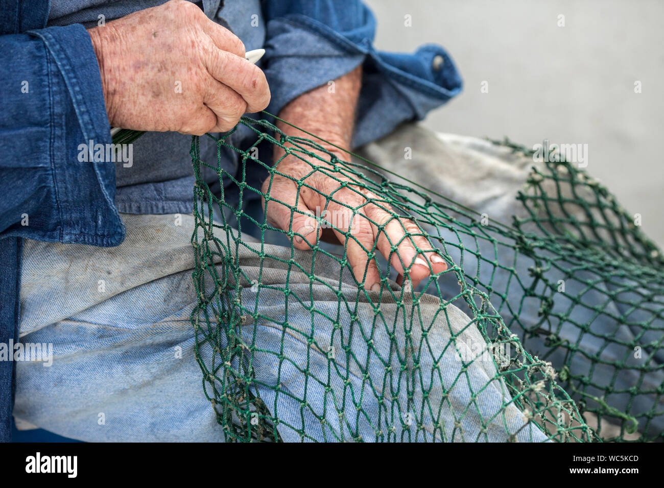 Hands of commercial fisherman mending nets Stock Photo - Alamy
