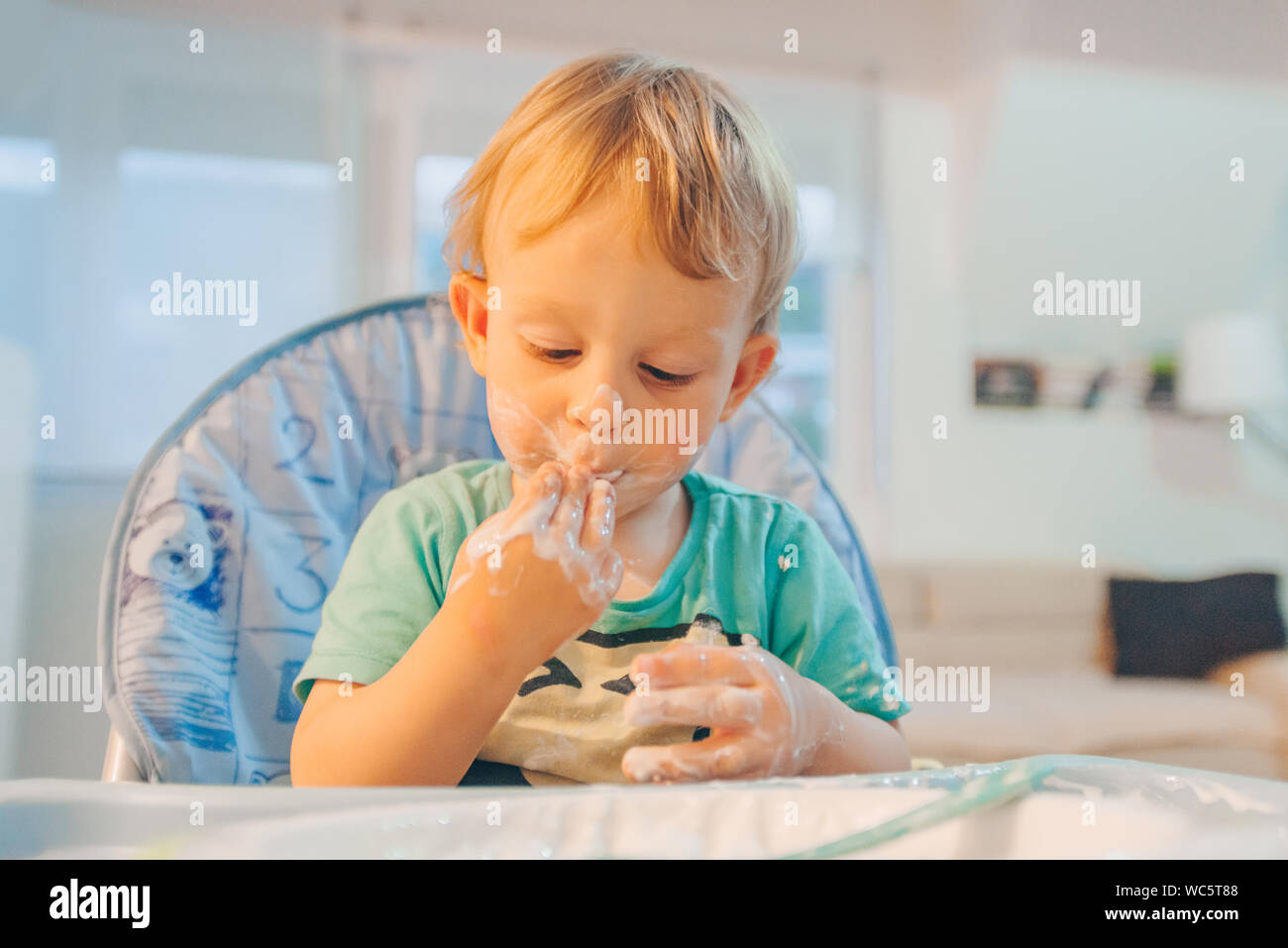 Adorable baby eating healthy food on kitchen with his hands Stock Photo ...