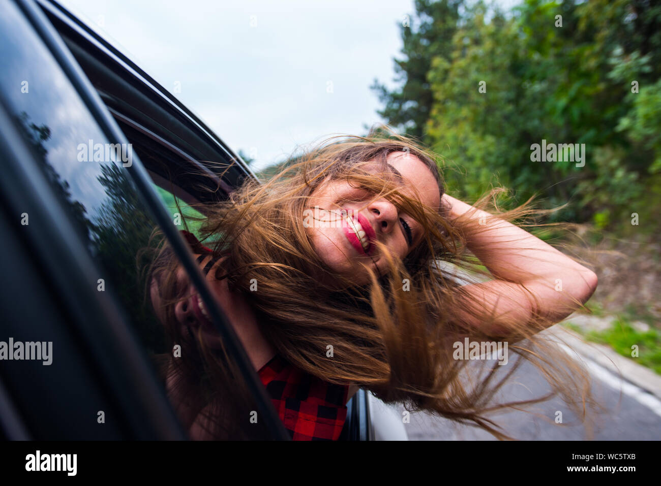 A female pulling her head out of a window while someone is driving her ...