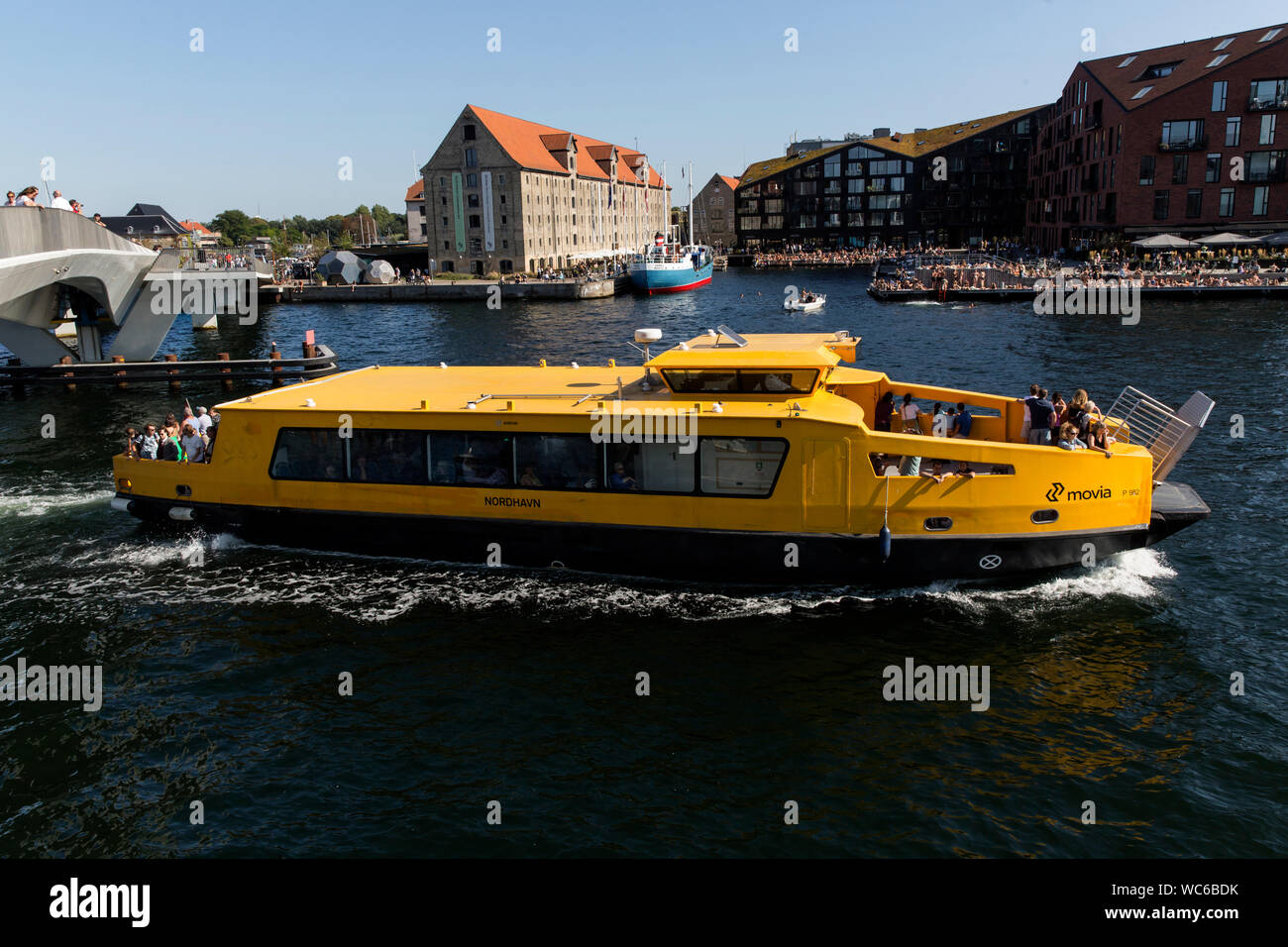 A water bus is sailing through the harbor channel next to Nyhavn and ...