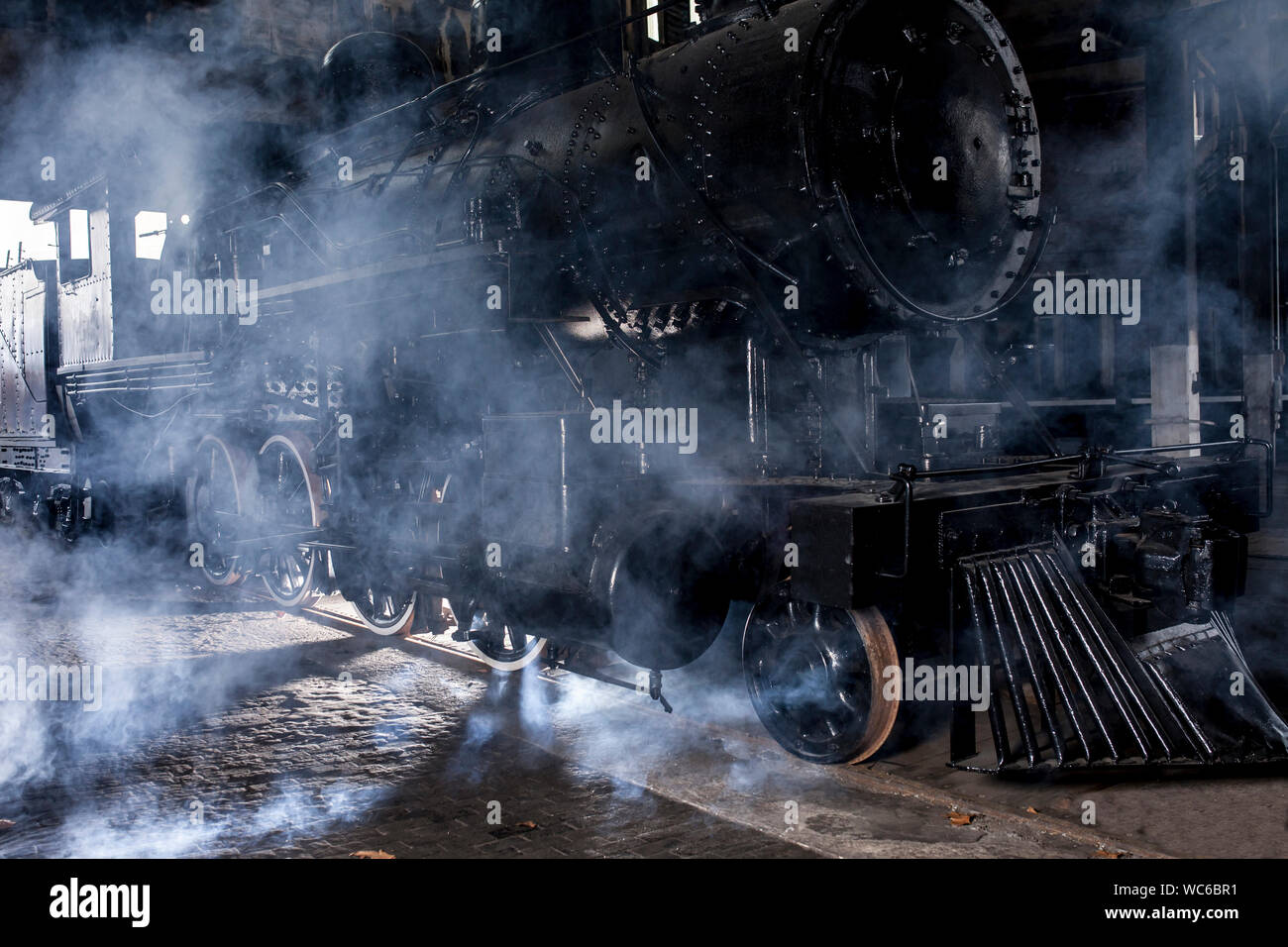 Steam locomotive at train station with dramatic lighting and steam ...