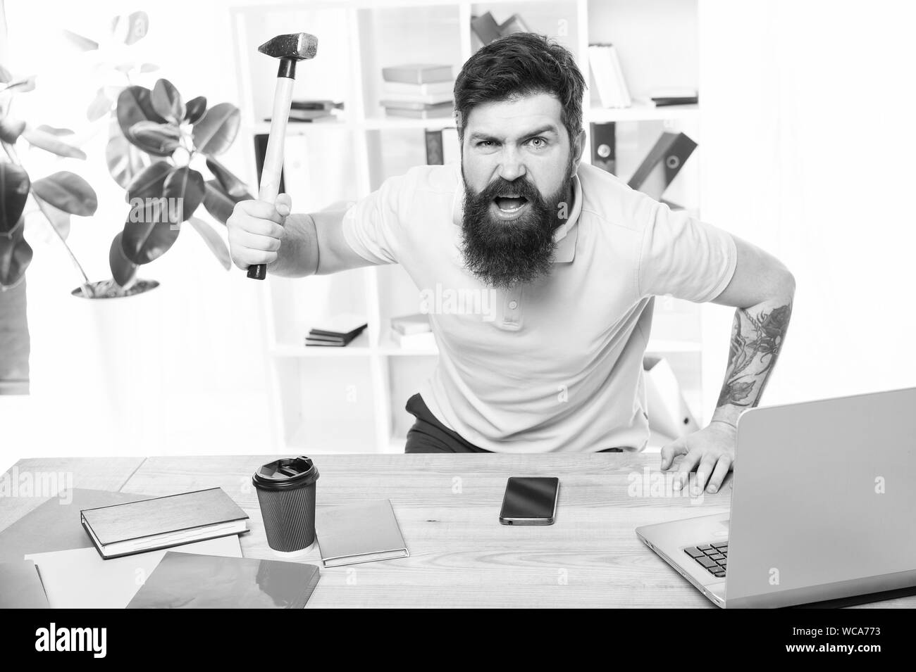 Frustrated office worker holding hammer poised ready to smash. Office ...