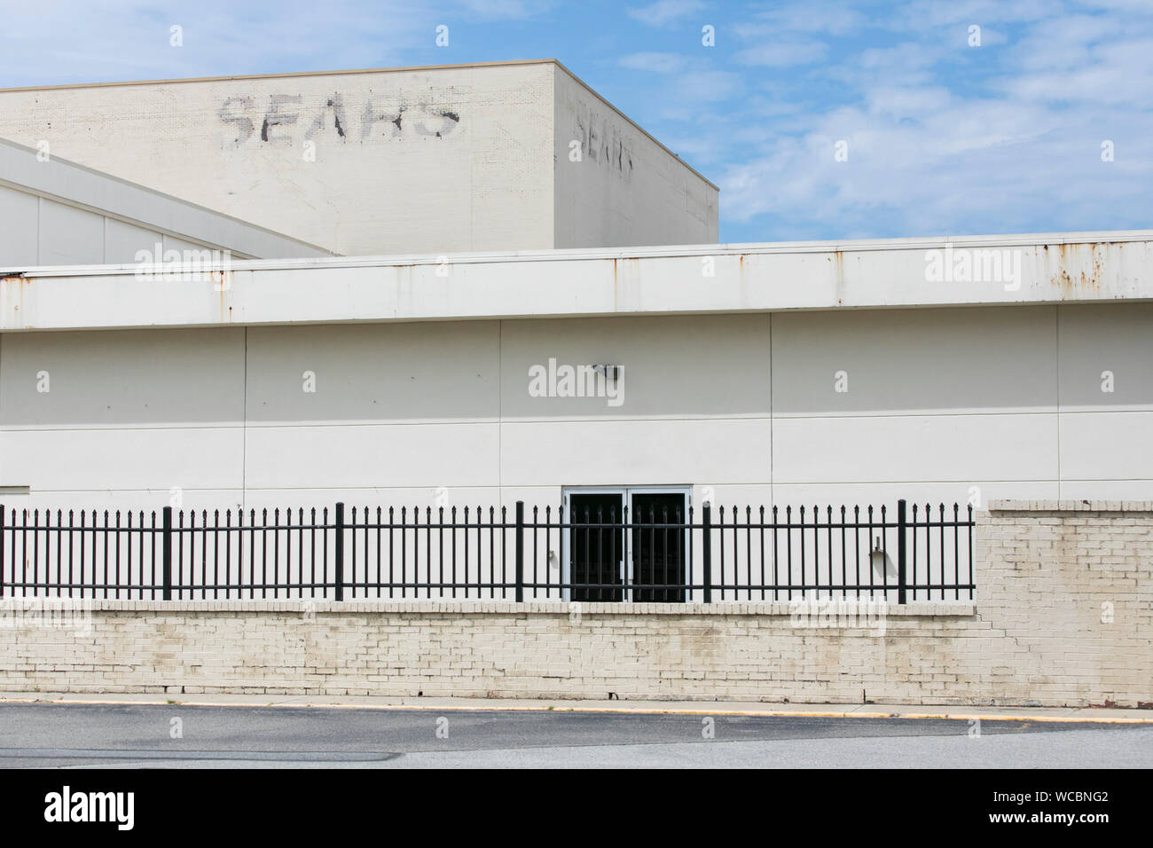 A faded outline of a logo sign outside of a closed and abandoned Sears ...