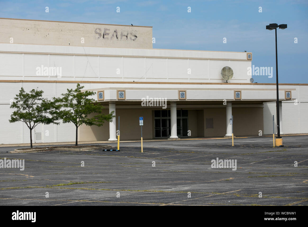 A faded outline of a logo sign outside of a closed and abandoned Sears ...