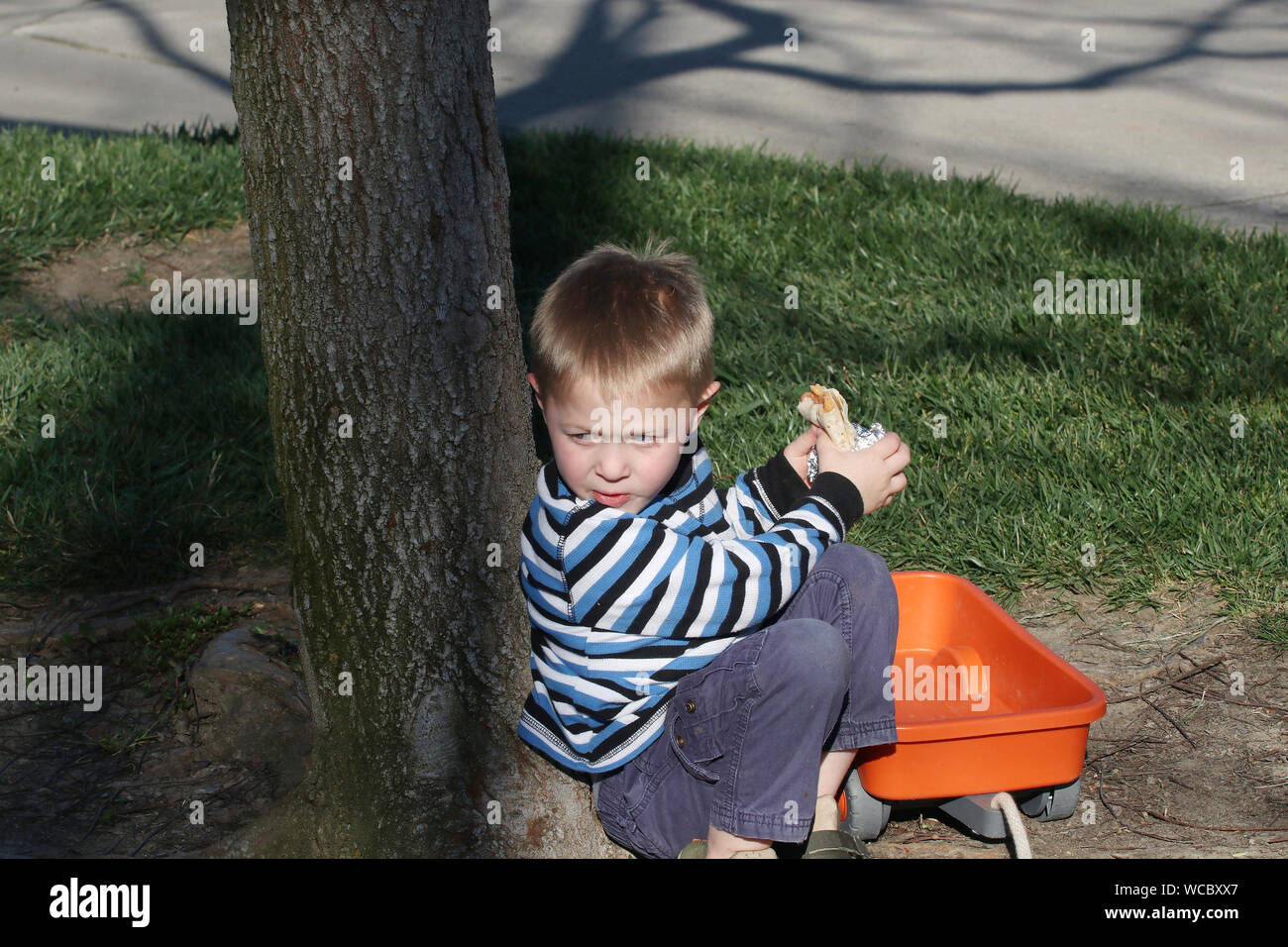 Young boy sneaking a burrito from the table hiding Stock Photo - Alamy