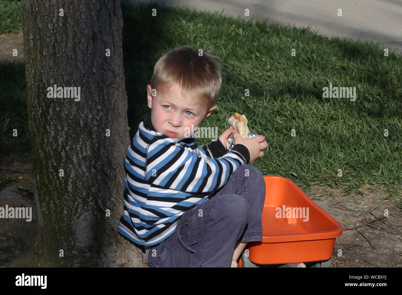 Young boy sneaking a burrito from the table hiding Stock Photo - Alamy
