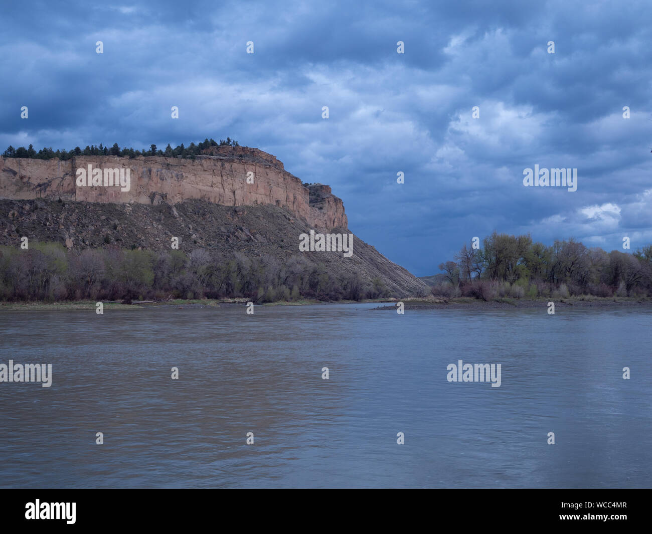 Sandstone cliffs along the Yellowstone River with storm clouds overhead ...