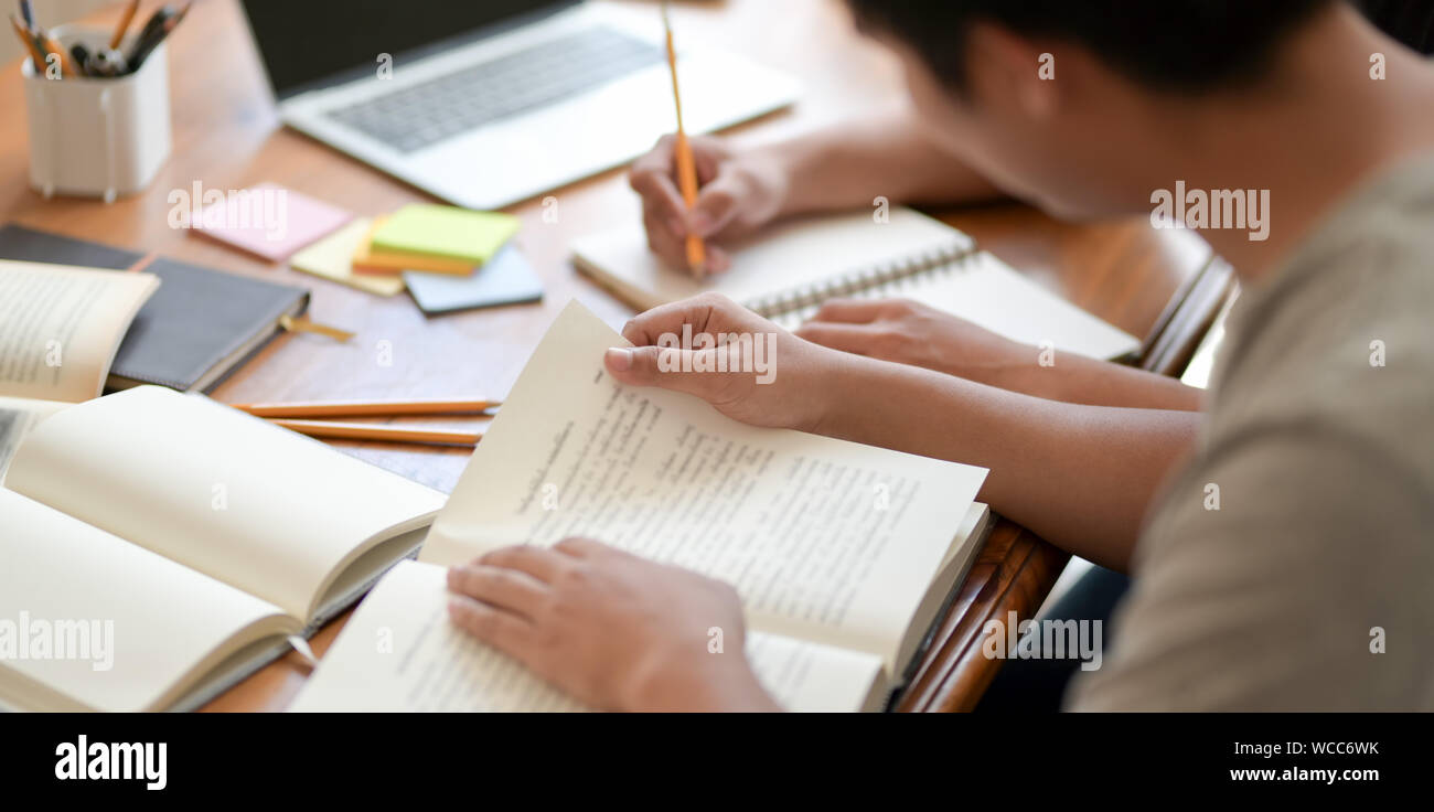 Hard-working college man reading books during the exam period with his ...