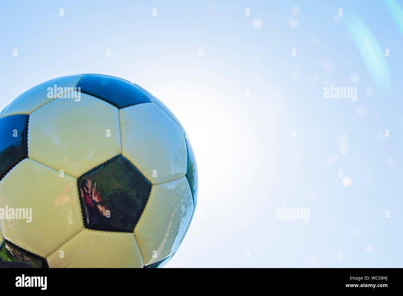Soccer ball on the background of the sun. Glare of sunlight. Place for ...