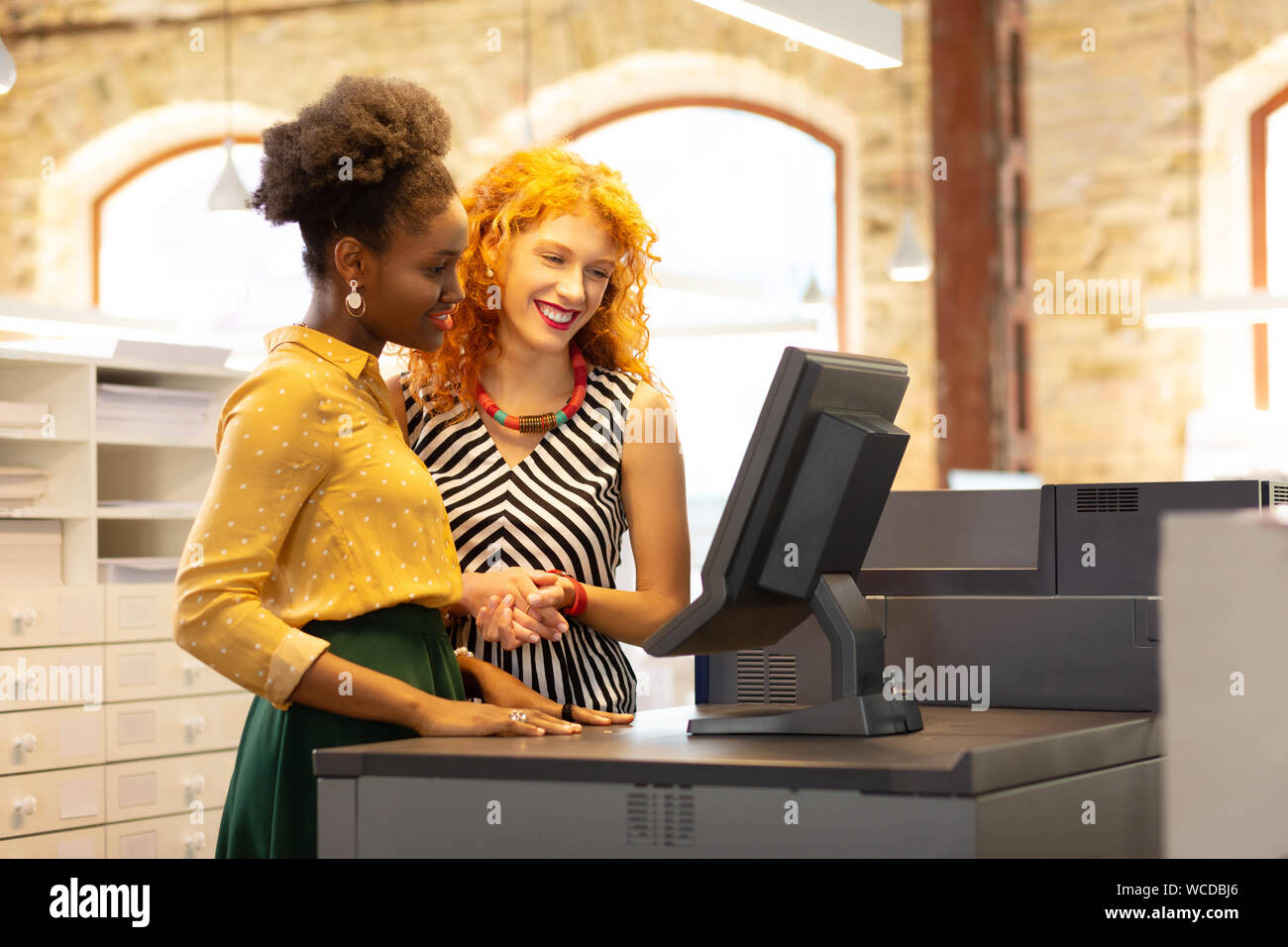 Businesswoman teaching employee to use cashier system Stock Photo - Alamy