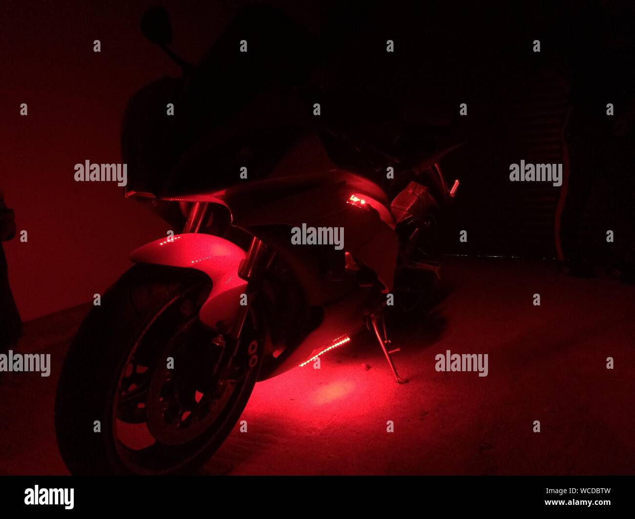 Red Illuminated Motorcycle Parked In Darkroom Stock Photo - Alamy