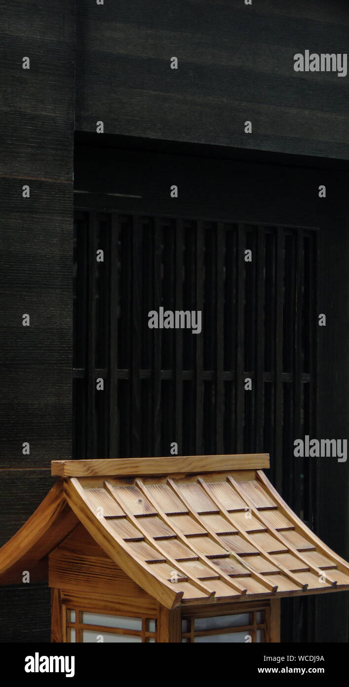 Traditional wooden Japanese lamp outside black restaurant sliding door ...