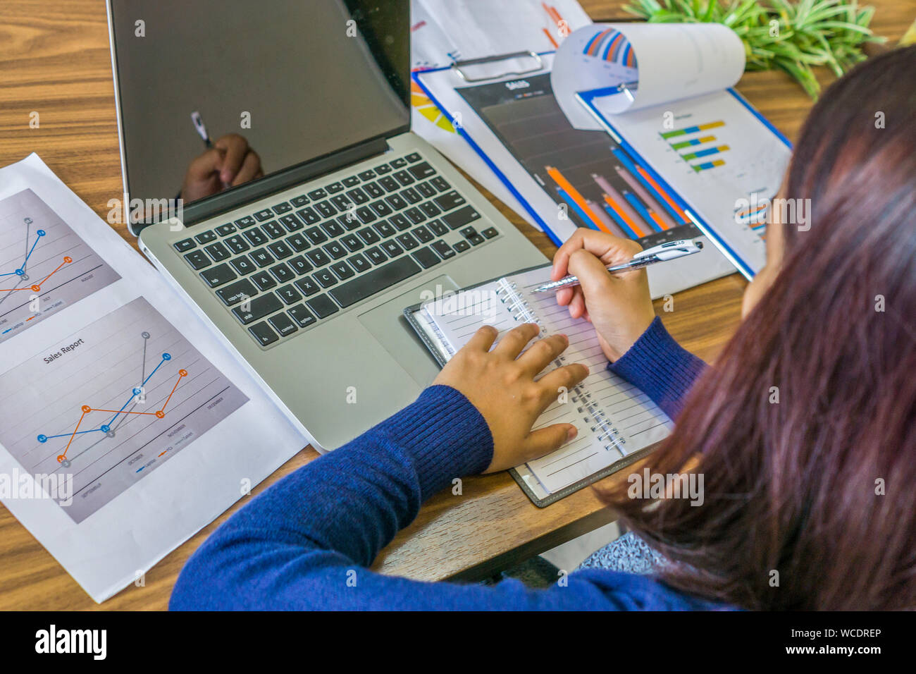 Asian financial accountant writing notebook next to laptop and ...