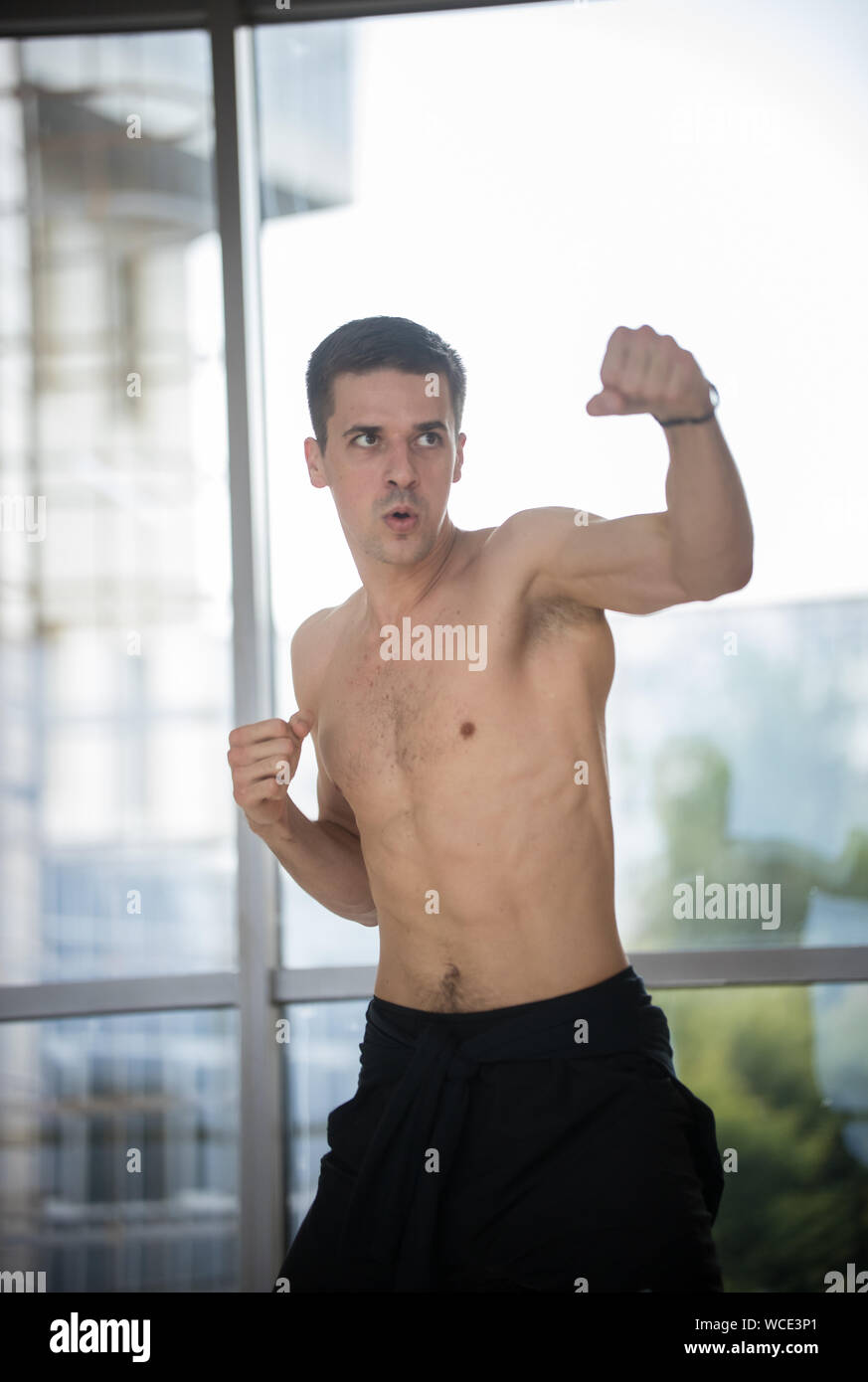 An athletic man boxer standing in fighting pose in the studio. Mid shot ...