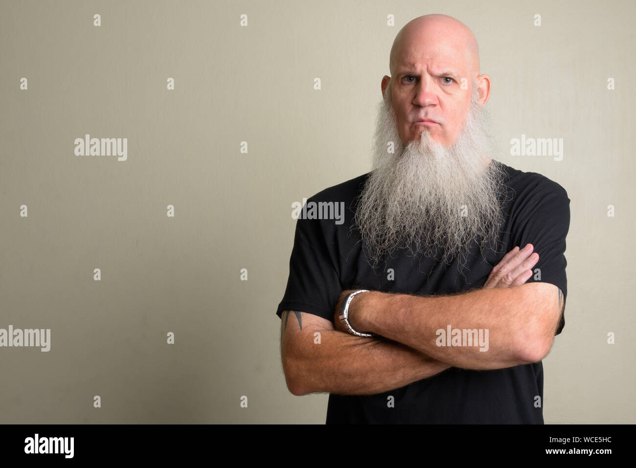 Angry mature bald man with long gray beard crossing arms Stock Photo ...