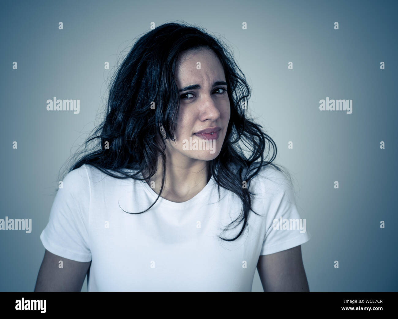 Young latin woman feeling disgust looking at something unpleasant ...