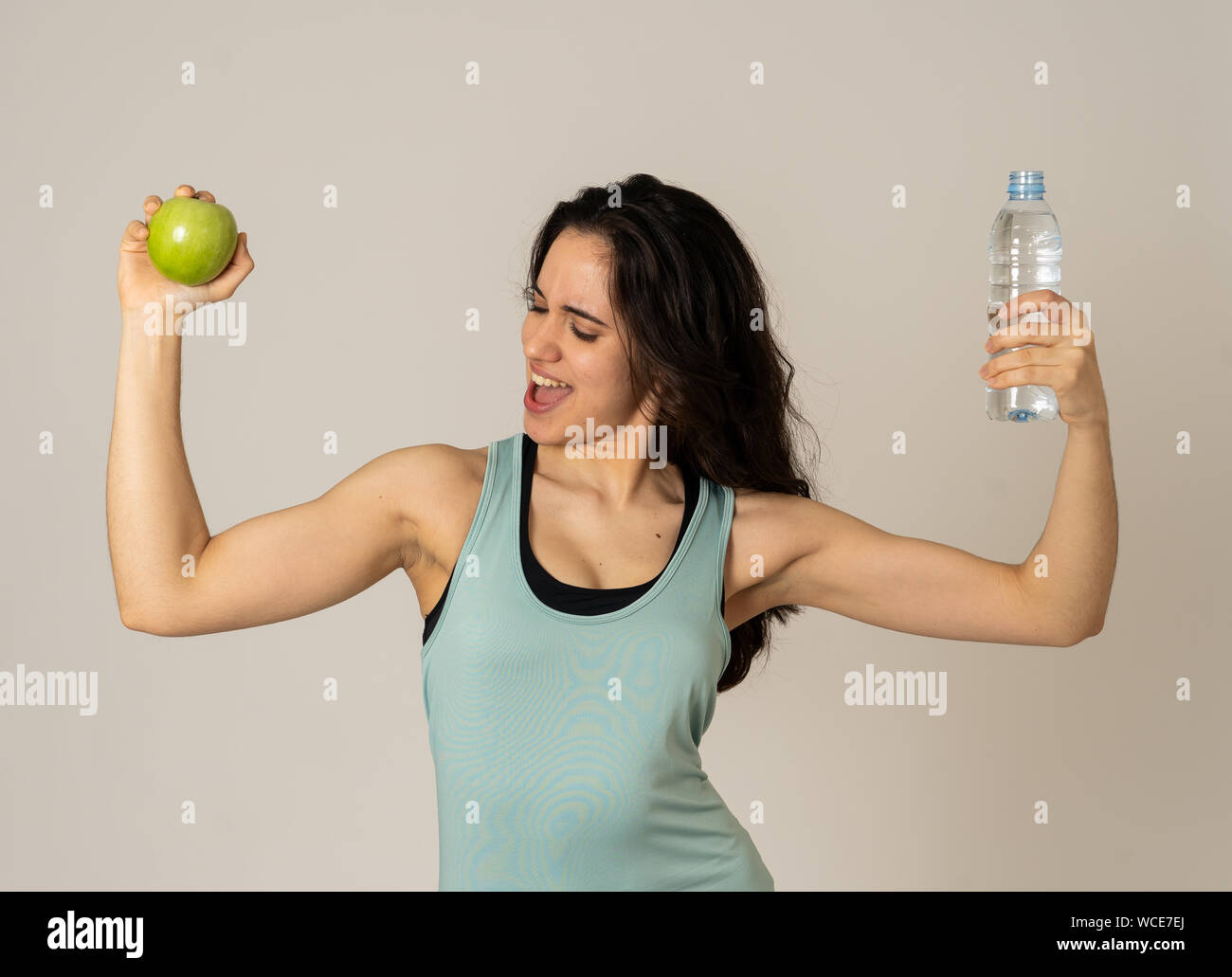 Happy fitness woman smiling holding an apple and water bottle feeling ...
