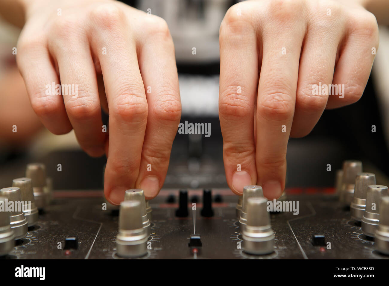 Close up wide angle shot of female dj hands adjusting frequency knobs ...